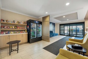 A lobby area with a vending machine, snack shelves, seating, and a reception desk.