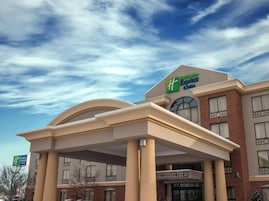 Um hotel Holiday Inn Express com entrada em destaque e um céu azul límpido.