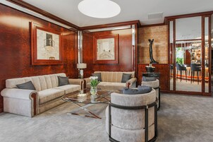 Uma sala de estar moderna com um sofá bege, uma mesa de centro de vidro e um vaso decorativo.