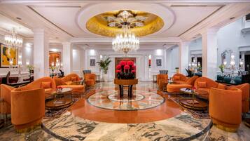 Um hall amplo com um lustre imponente, assentos confortáveis e uma decoração floral central.