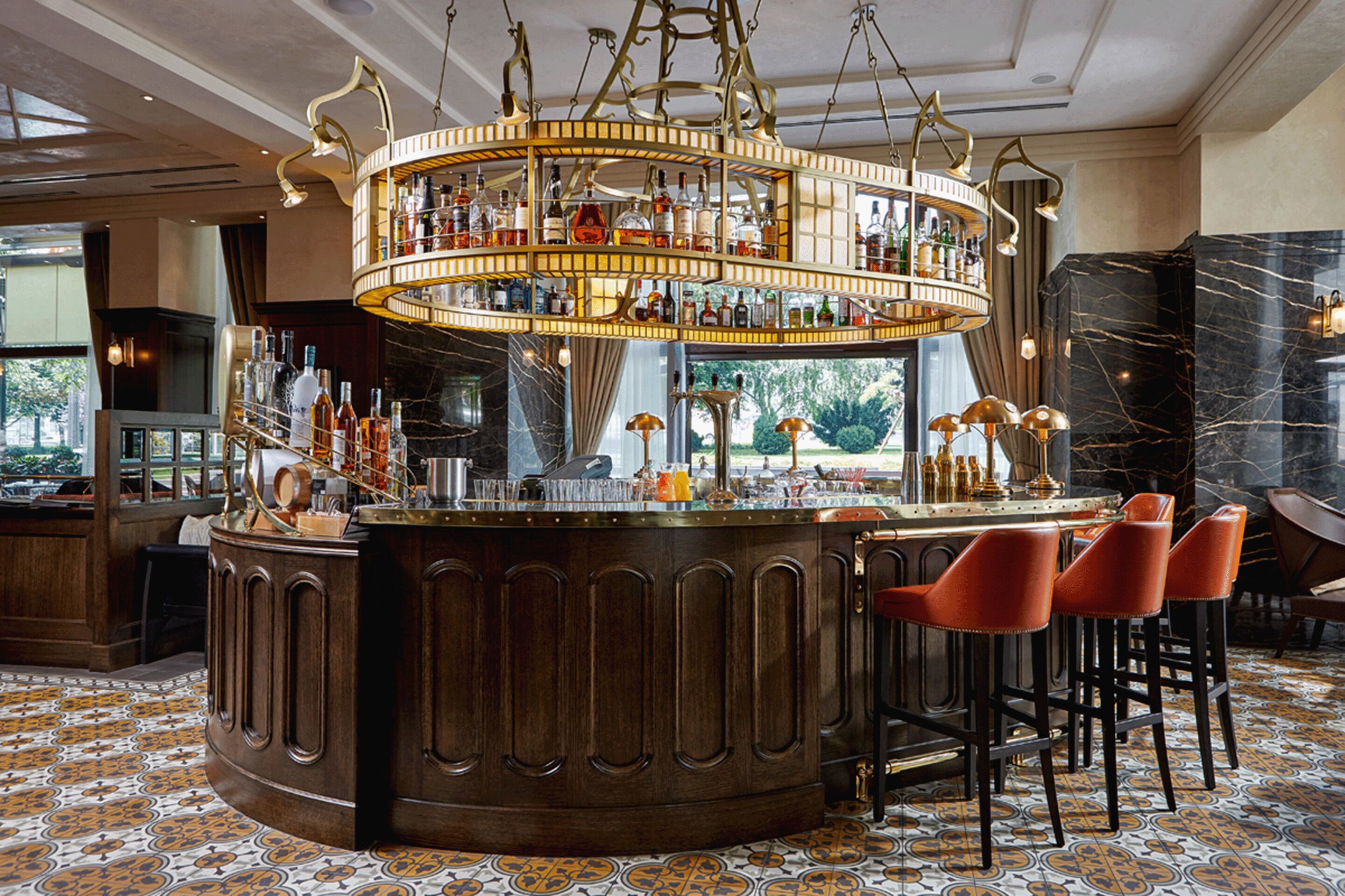 Uma área de bar com balcão circular, vários bancos e um candelabro.