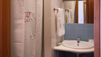 Um banheiro com pia branca, azulejos azuis e cortina de chuveiro com um logotipo.