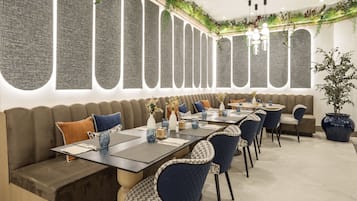 Um restaurante moderno com um amplo banco, mesas redondas e cadeiras azuis.
