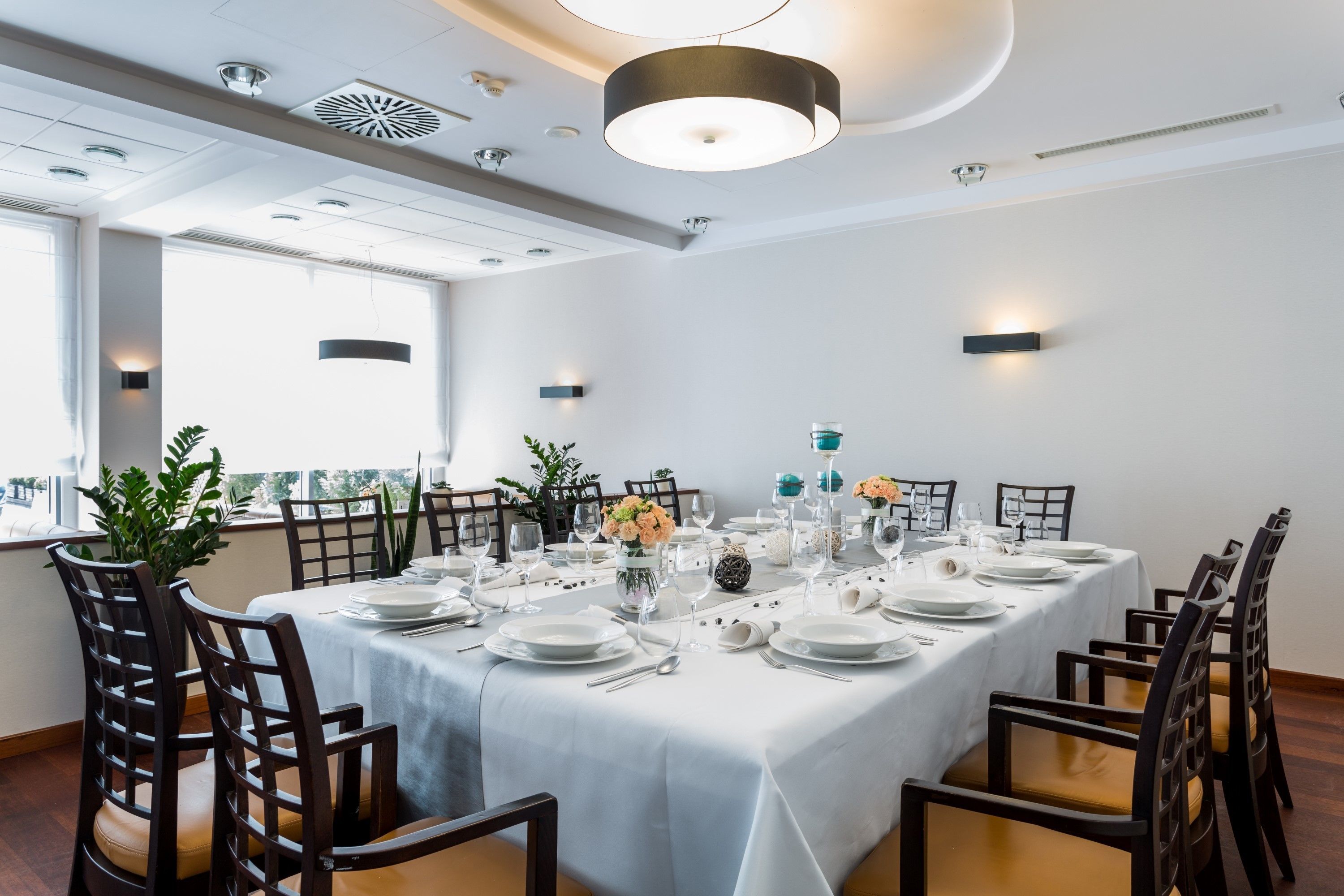 Uma sala de jantar com uma mesa comprida posta para refeição, rodeada por cadeiras.