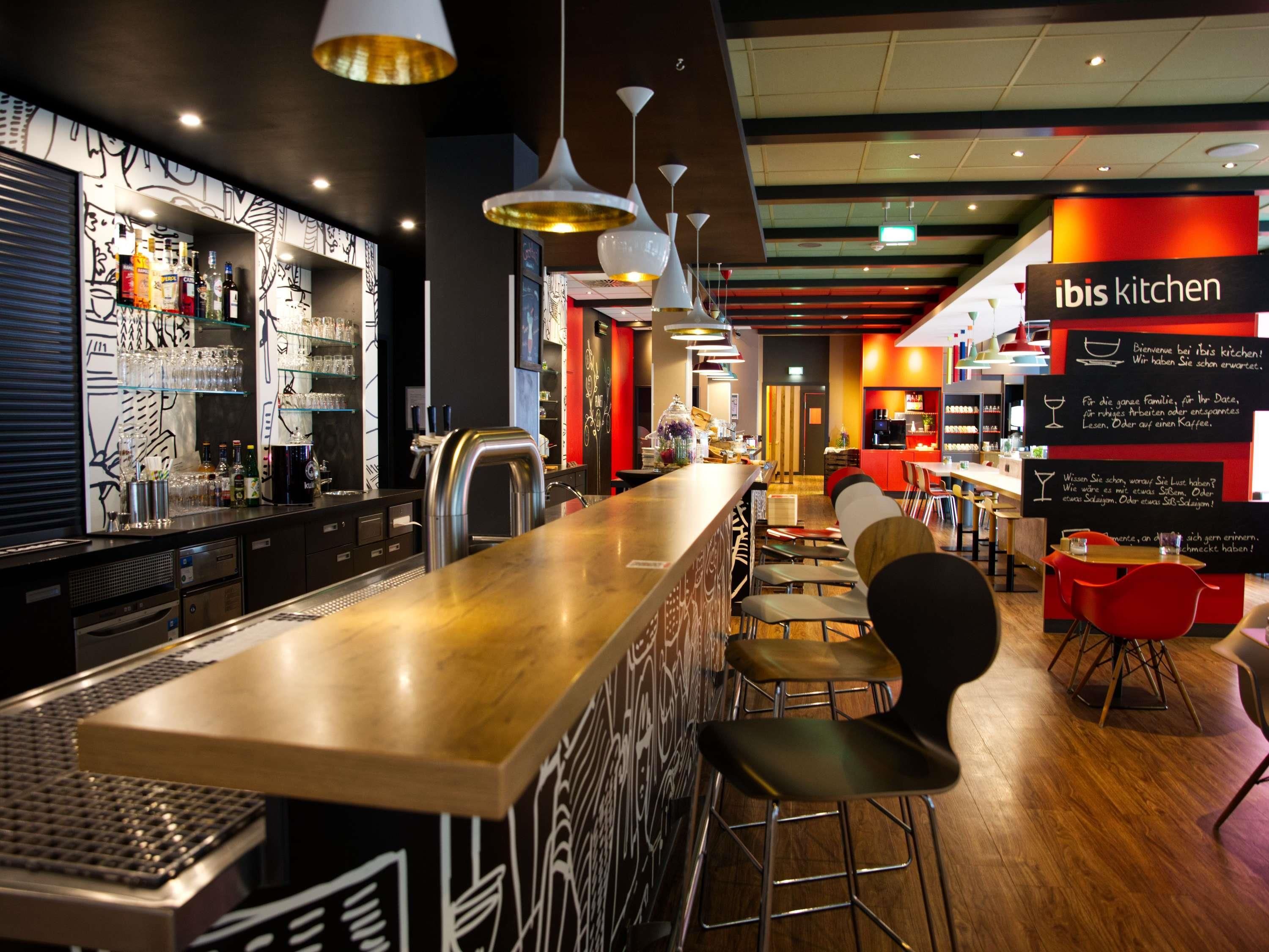 Cozinha moderna com bancada de bar, banquetes e luminárias pendentes.