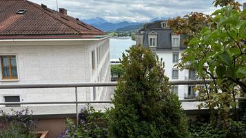 Um edifício branco com telhado de telhas vermelhas, com vista para um corpo d'água e montanhas.