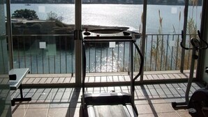Varanda com vista para um lago, esteira e uma mesa pequena.