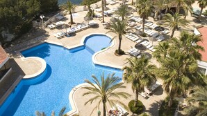 Um resort com piscina, espreguiçadeiras e palmeiras.