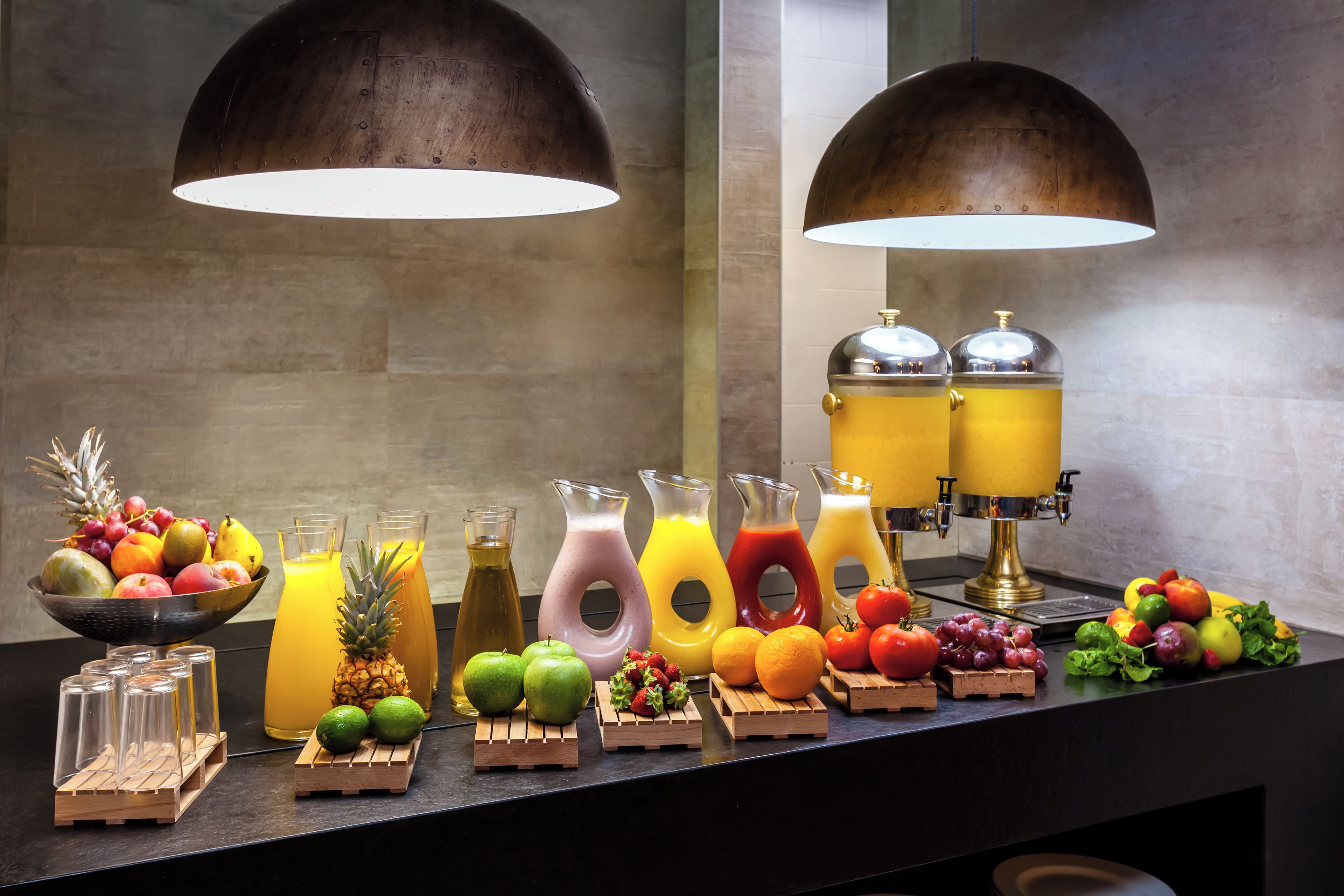 Um buffet de café da manhã com diversas frutas, sucos e uma máquina de café.