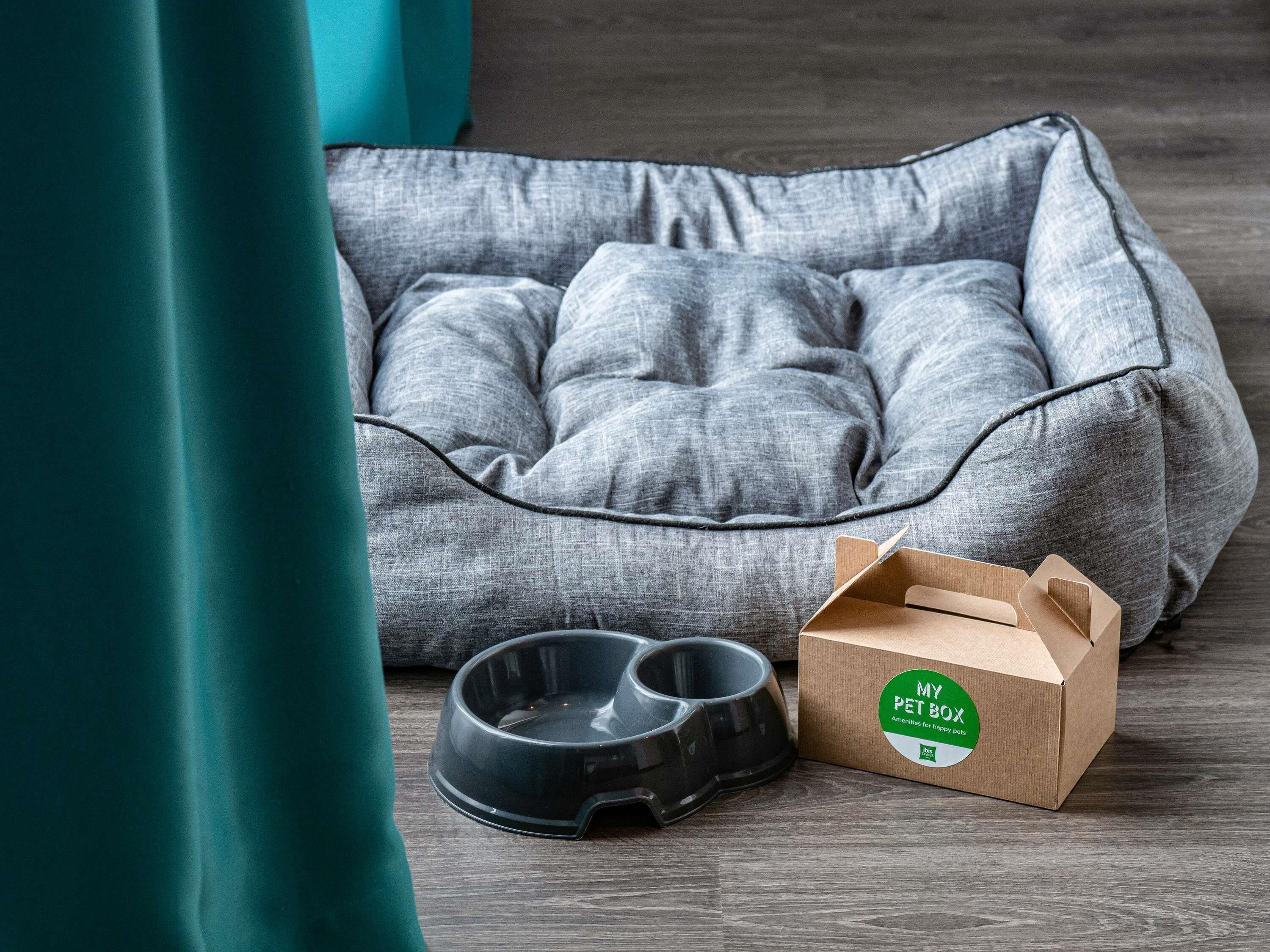 Uma cama para animais de estimação, duas tigelas e uma caixa de papelão com etiqueta.