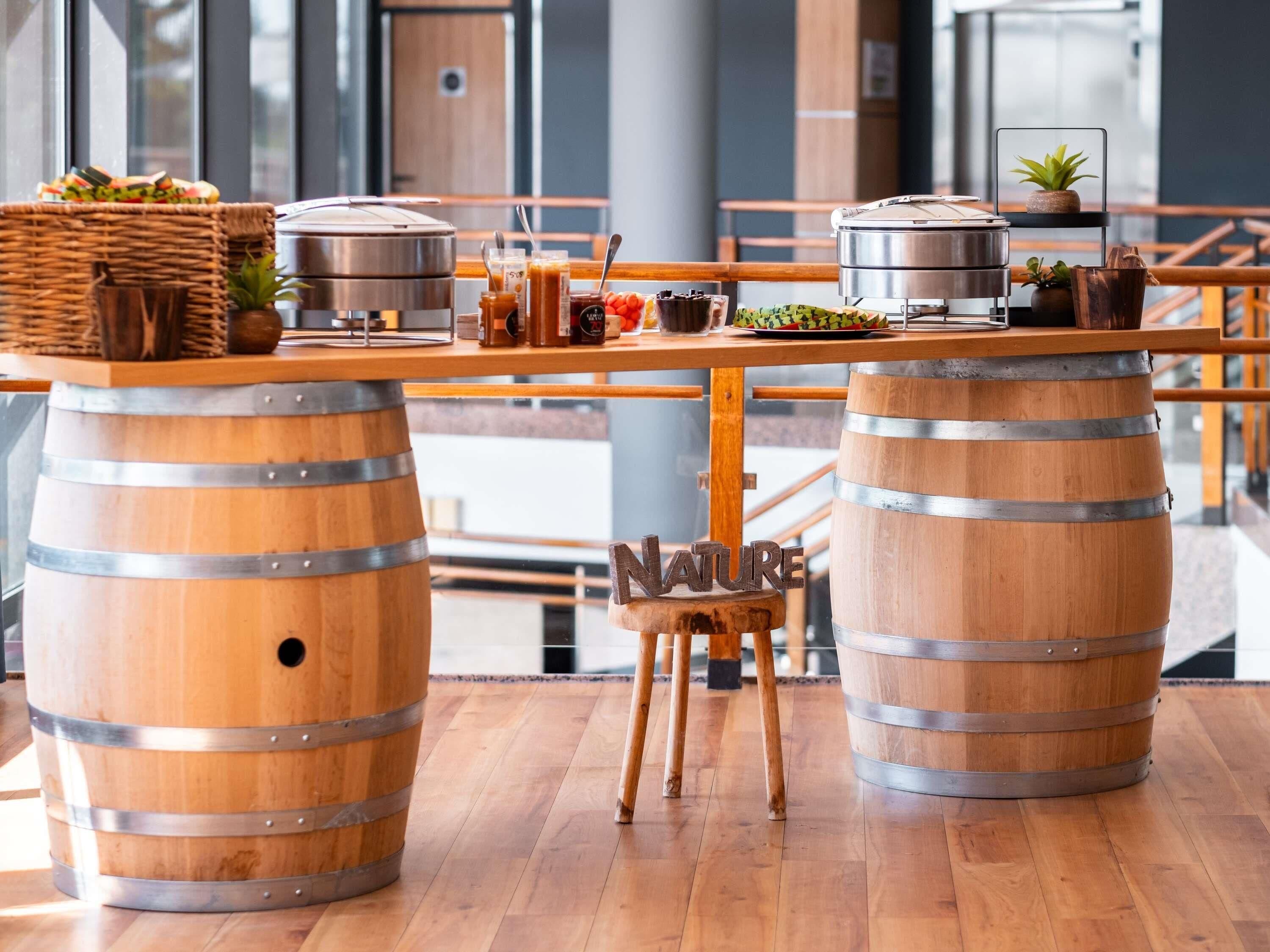 Uma área de bar com barris de madeira, uma máquina de café e uma pequena mesa com uma planta.