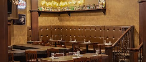 Um restaurante com letreiros de neon, móveis de madeira e um espaço de bar.