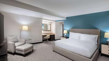 Quarto de hotel com uma cama grande, uma escrivaninha, uma cadeira e uma televisão.