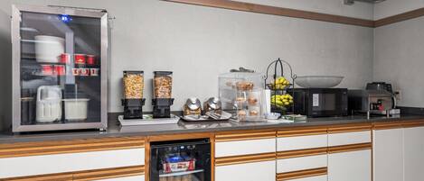 Uma cozinha moderna com geladeira, micro-ondas, cafeteira e lava-louças.