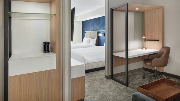 Quarto de hotel com cama, secretária, cadeira e máquina de café.