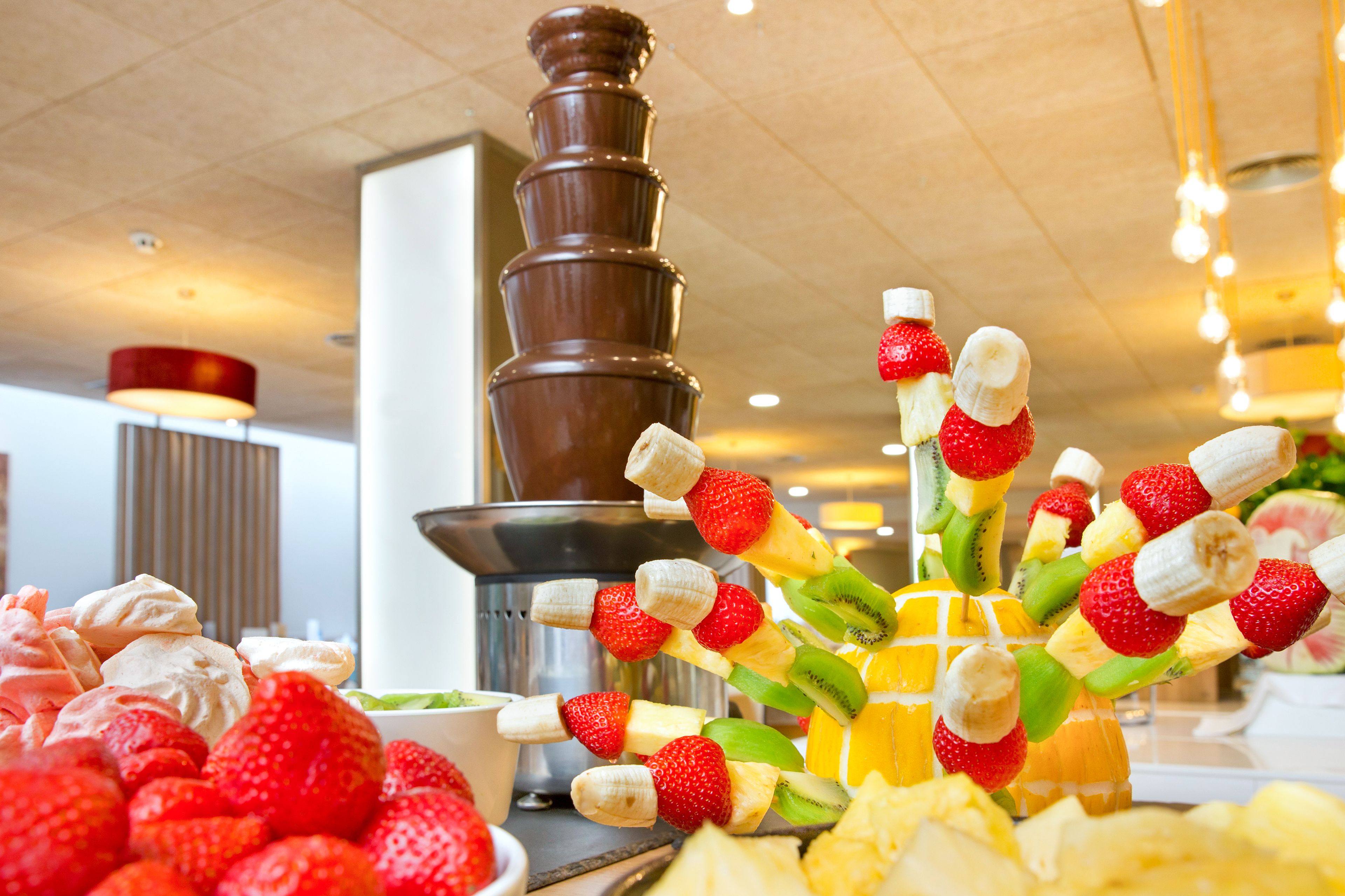 Uma fonte de chocolate com espetinhos de fruta em um buffet.