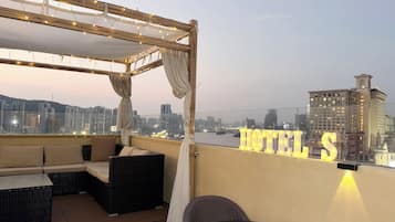 Uma varanda com vista para o horizonte urbano, um toldo com luzes de cordão e uma placa que diz 'HOTELS'.
