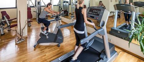 Uma academia com esteiras, bicicletas ergométricas e aparelhos de musculação.
