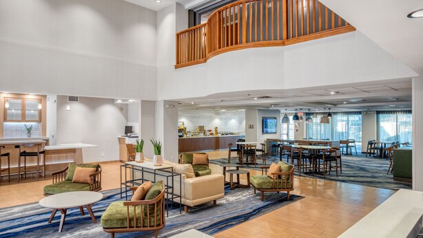 Um hall amplo com teto alto, cozinha e área de refeições com várias mesas e cadeiras.