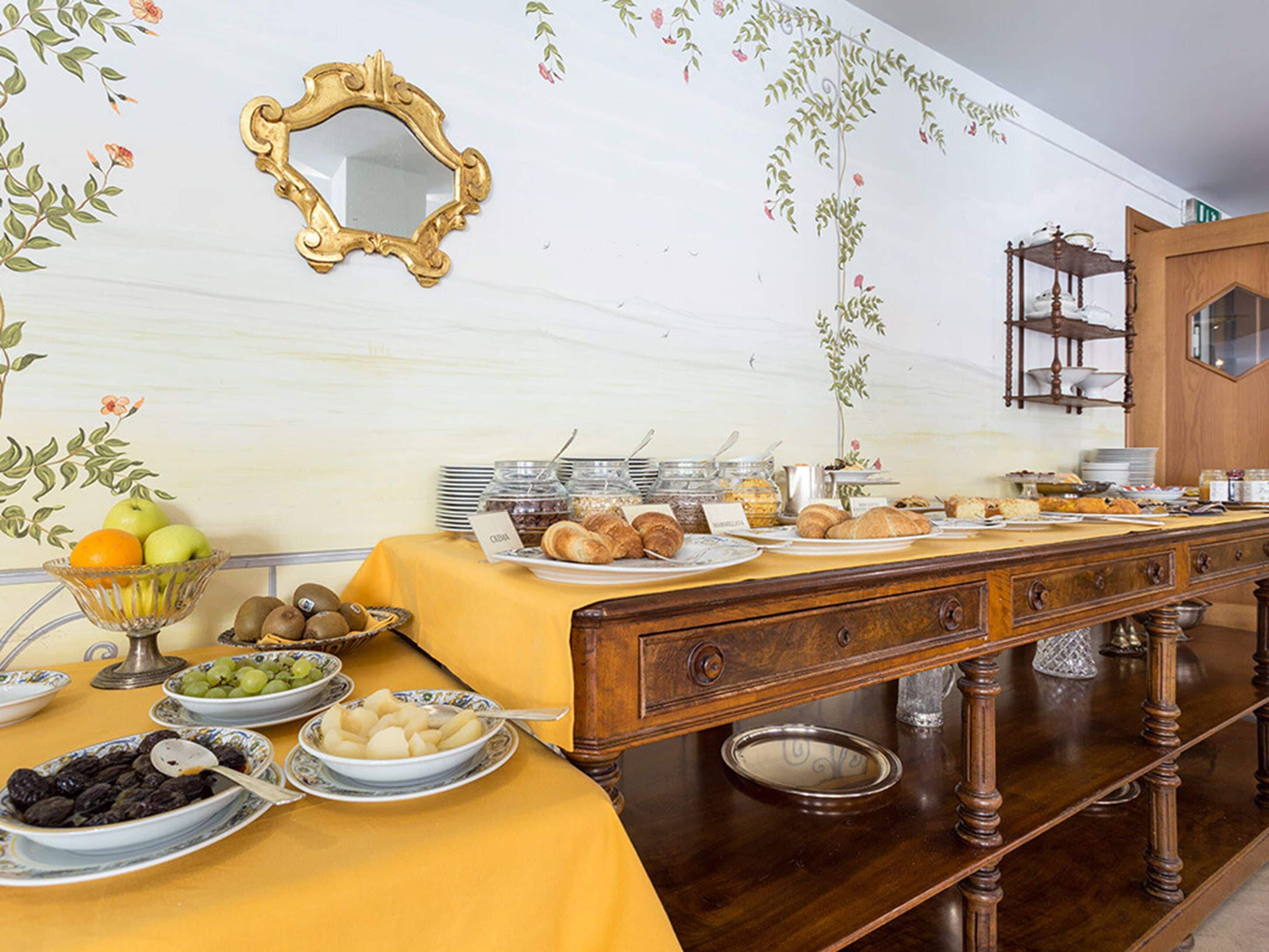 Disposição de buffet com diversos alimentos e um espelho na parede.