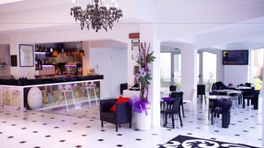 Um lobby de hotel moderno com área de bar, espaços de estar e um lustre decorativo.