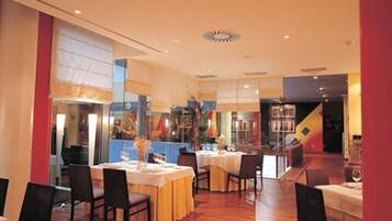 Um restaurante com várias mesas e cadeiras, piso de madeira e design moderno no teto.