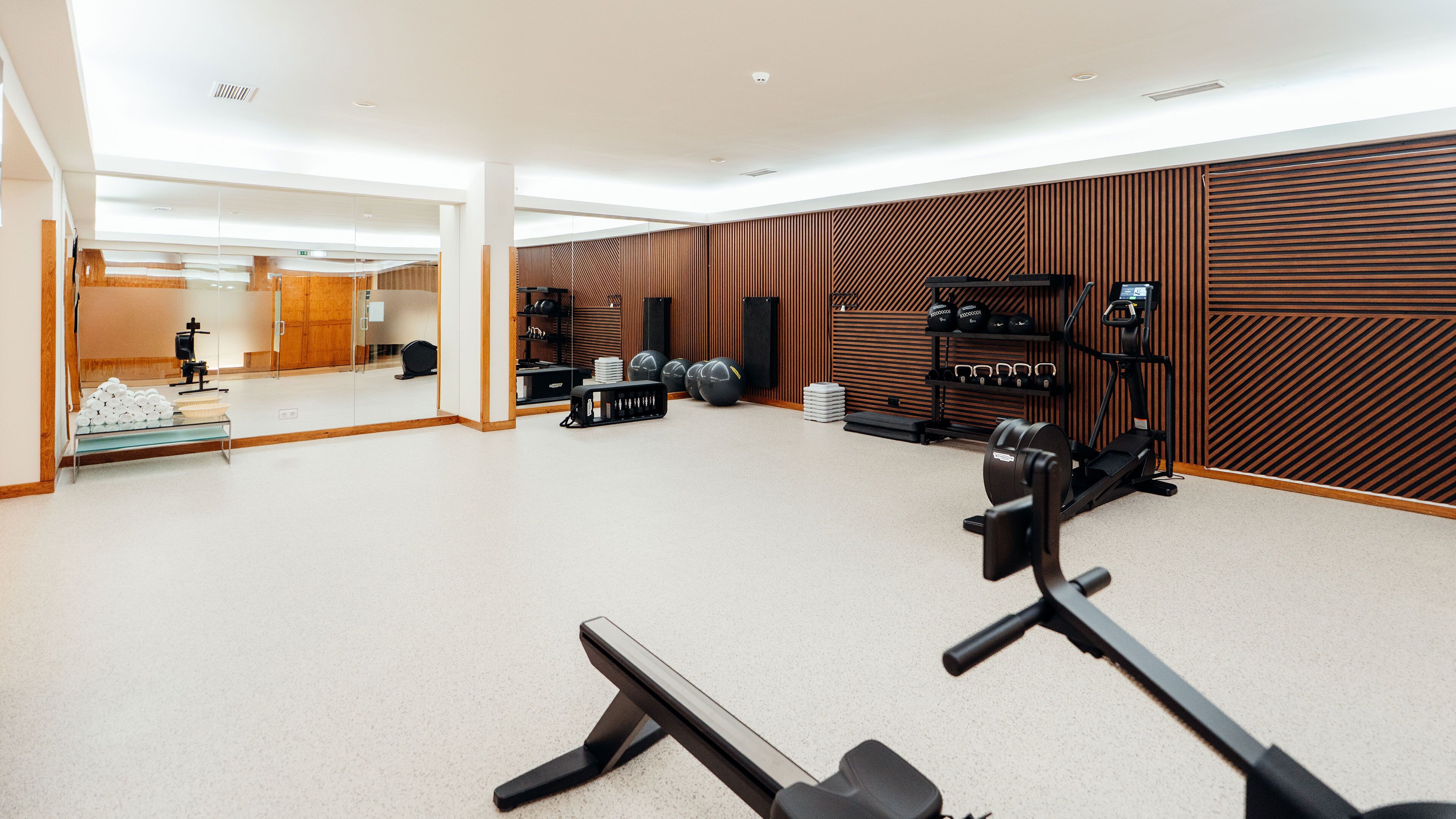 Academia moderna com equipamentos de ginástica, espelho e parede de painéis de madeira.