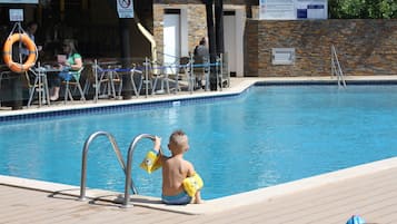 Uma área de piscina com um salva-vidas, um espaço coberto para sentar e um aviso com as regras da piscina.