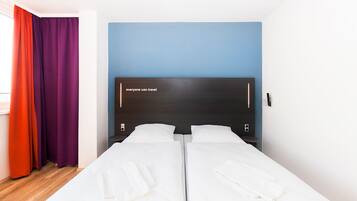 Uma cama de casal com cabeceira escura e parede azul ao fundo.