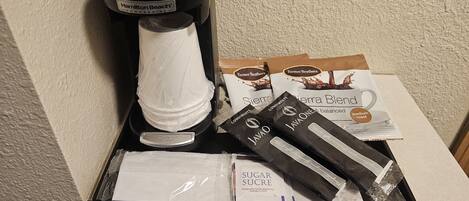 Uma cafeteira, cápsulas de café e um saquinho de açúcar numa bandeja.