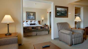 Quarto de hotel com cama, cadeira, mesa e controle remoto.