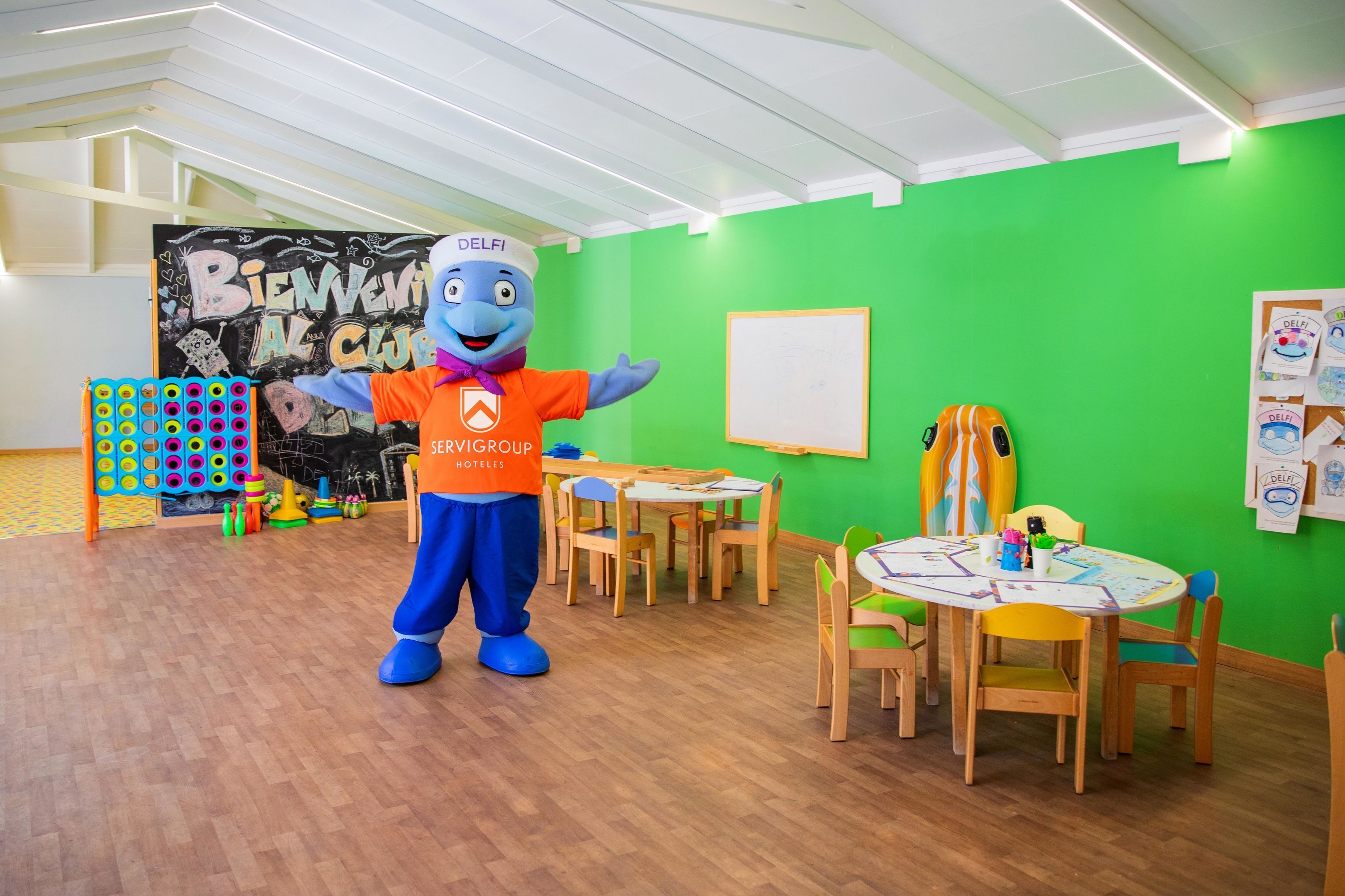 Um mascote em um quarto com paredes verdes, móveis de madeira e um mural.