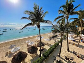 Na praia, espreguiçadeiras, guarda-sóis, toalhas de praia 