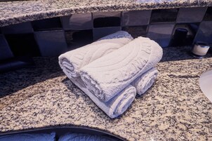 Uma pilha de toalhas brancas sobre uma bancada de granito em um banheiro.