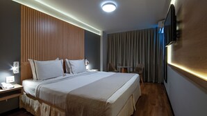 Quarto de hotel com uma cama grande, mesas de cabeceira, televisão de tela plana e uma luminária de teto.