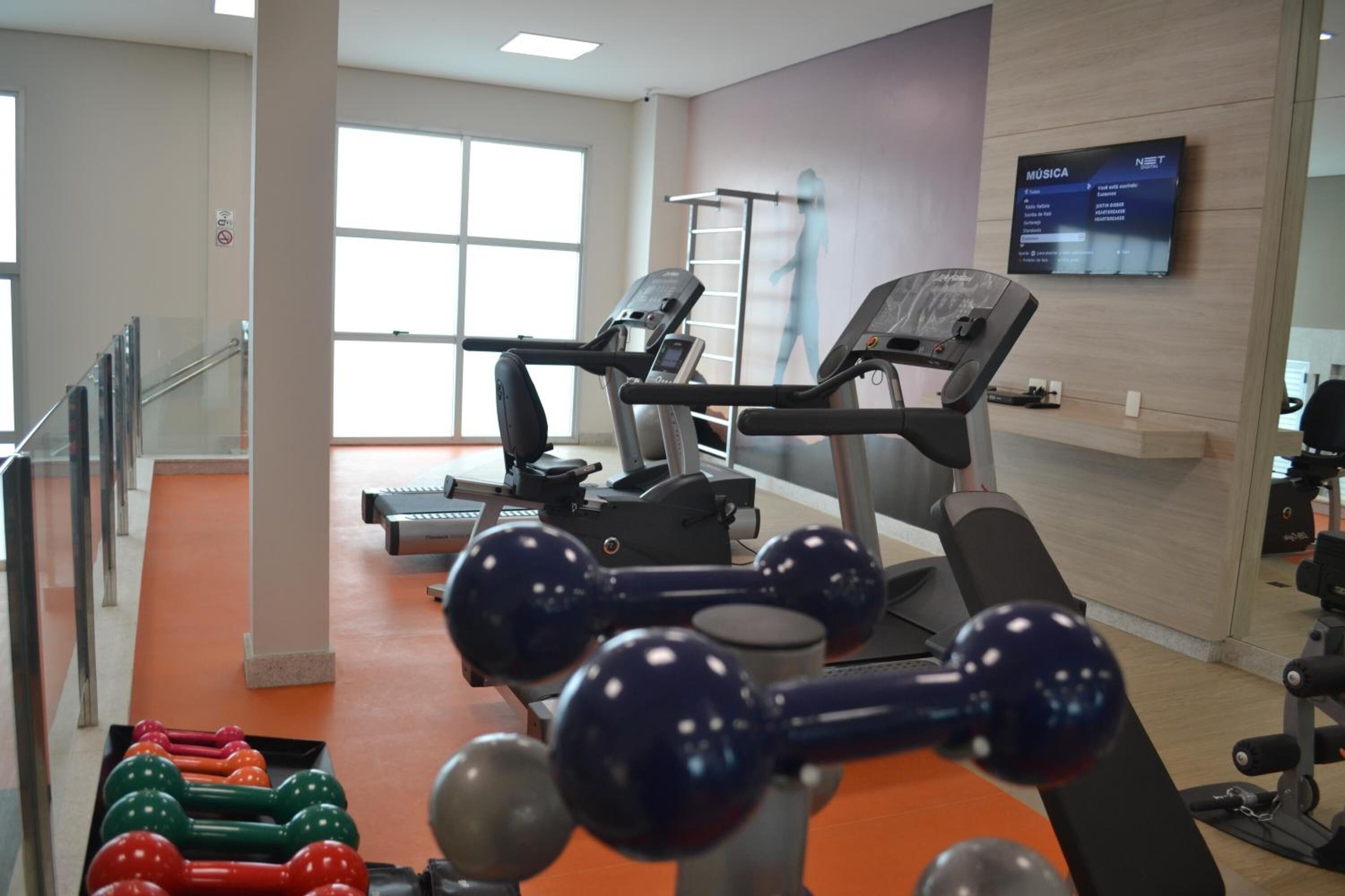 Uma academia com esteiras, aparelhos de musculação e halteres.