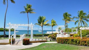 Um gazebo branco com vista para o oceano e palmeiras.