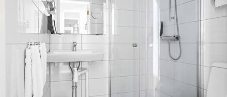 Uma casa de banho moderna com cabine de duche em vidro, lavatório branco e sanita.