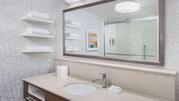 Uma casa de banho moderna com um espelho grande, uma pia redonda e toalheiros embutidos.