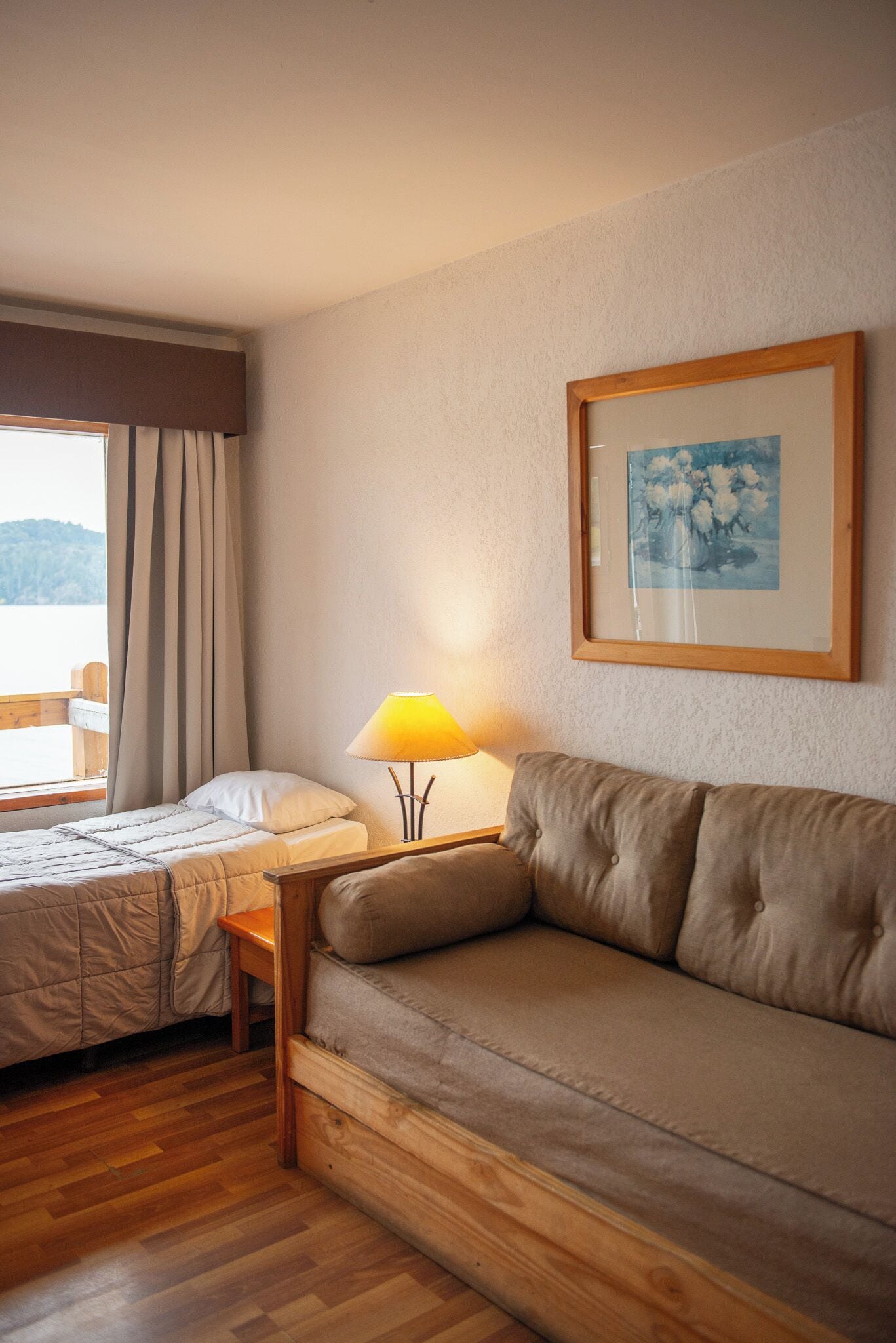 Um quarto com uma cama, um sofá, uma luminária e um quadro na parede.