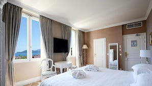 Quarto de hotel com uma cama grande, televisão, secretária e uma cadeira.