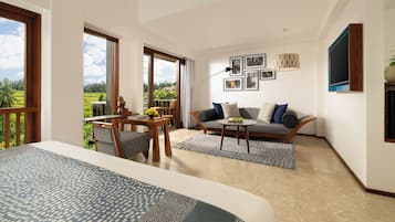 Quarto com cama, sofá, mesa de jantar e vista para uma paisagem verde.