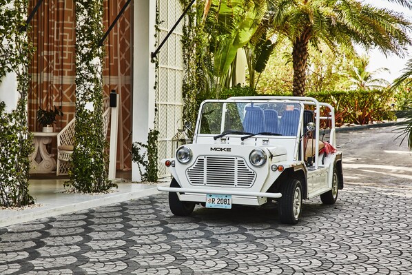 Um veículo Moke antigo estacionado numa rua de calçada estampada.