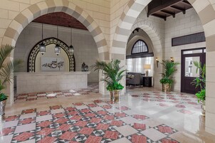 Um hall com piso estampado, tetos em arco e plantas em vasos.
