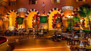 Um hall com várias áreas de estar, uma fonte decorativa central e arcos com sinalização.