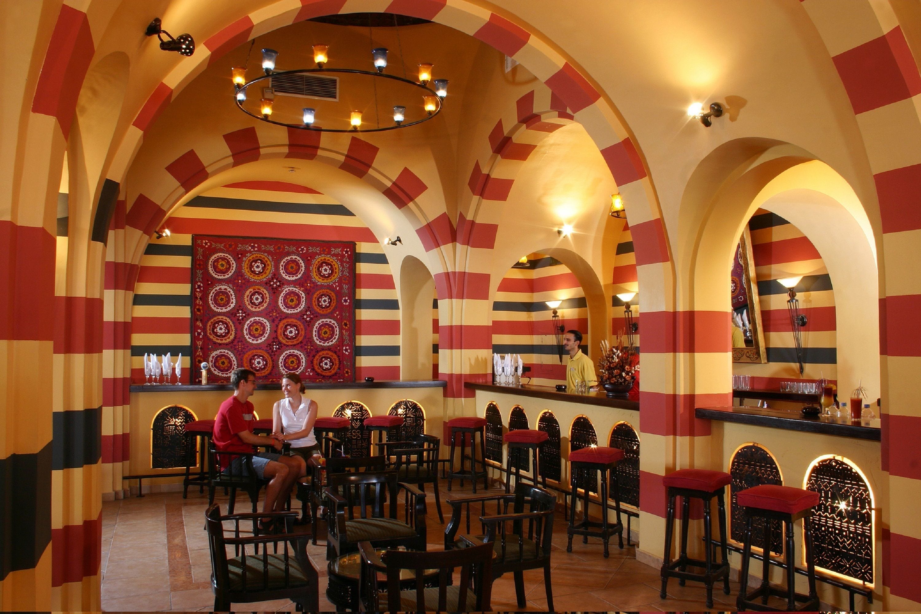 Restaurante com arcos listrados e um balcão central.