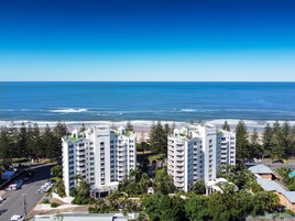Um hotel à beira-mar com vários edifícios altos, uma praia e um estacionamento.