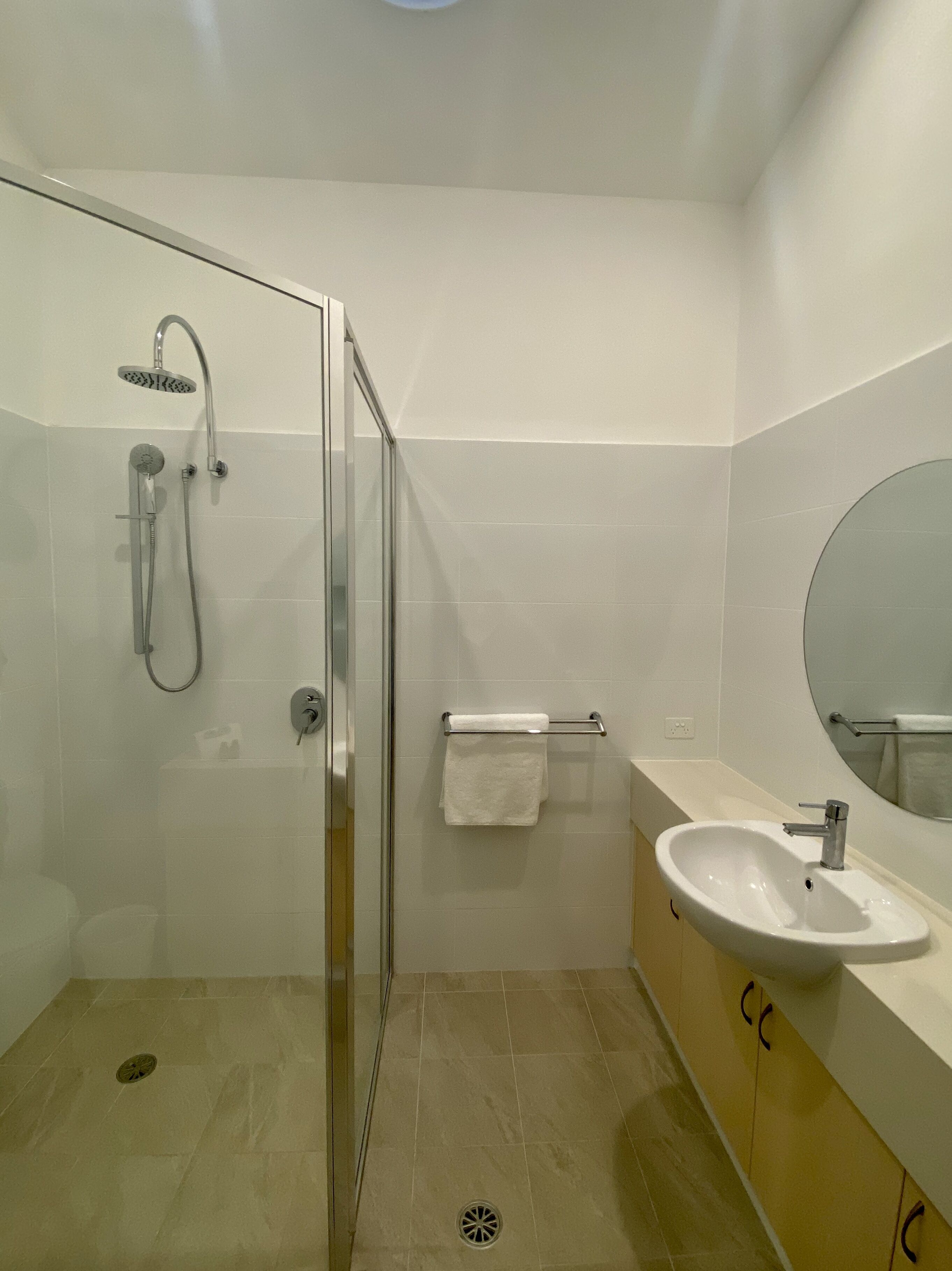 Uma casa de banho moderna com cabine de duche em vidro, uma pia e um espelho.