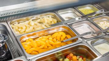 Buffet com diversas opções de comida, incluindo frutas, vegetais e uma salada.