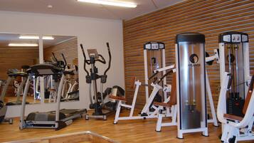 Uma academia com diversos equipamentos de exercícios, incluindo esteiras, elípticos e aparelhos de musculação.